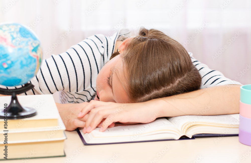 Back to school. Tired little child girl sleeping on the desk while ...