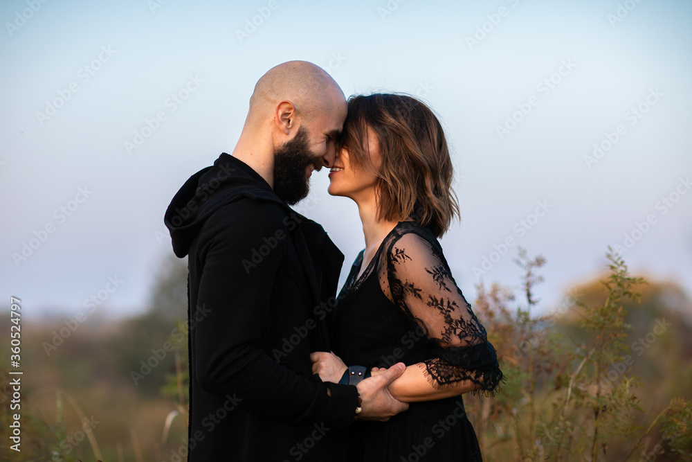 Portrait brunette woman and bald headed man with beard in black clothes ...