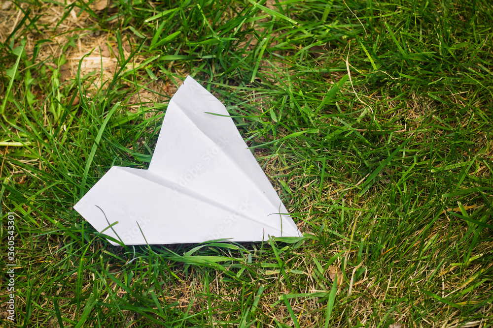 White paper airplane in green grass. Vacation concept, choice of ...