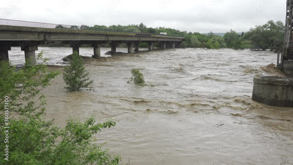 Bridge over the overflowing river. Stormy water flows. Extremely high ...