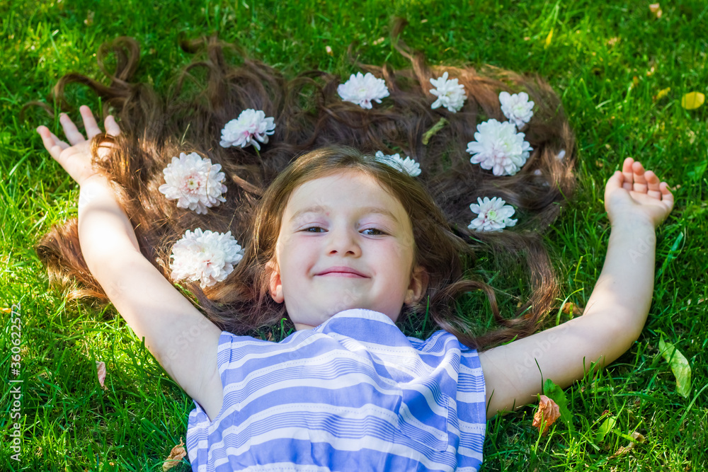 happy little girl, pretty little girl lying on grass with flowers foto ...