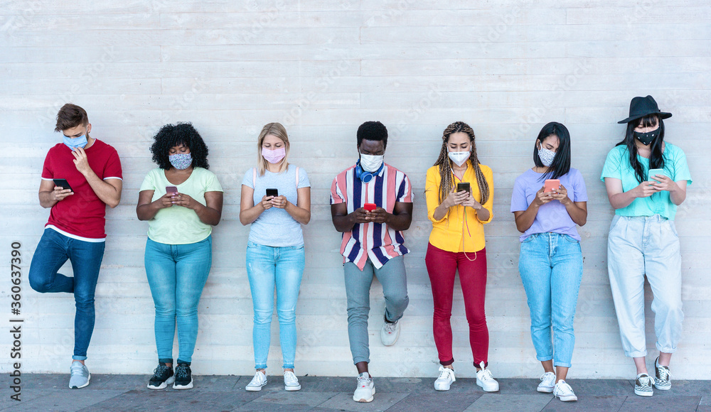 Young people wearing face safety masks using smart mobile phones while ...