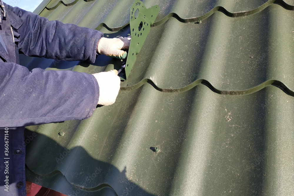 Installation by the master on a roof of the house of snow stops ...