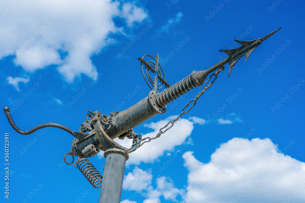Harpoon whaling weapon on a background of blue sky with clouds. Vintage ...