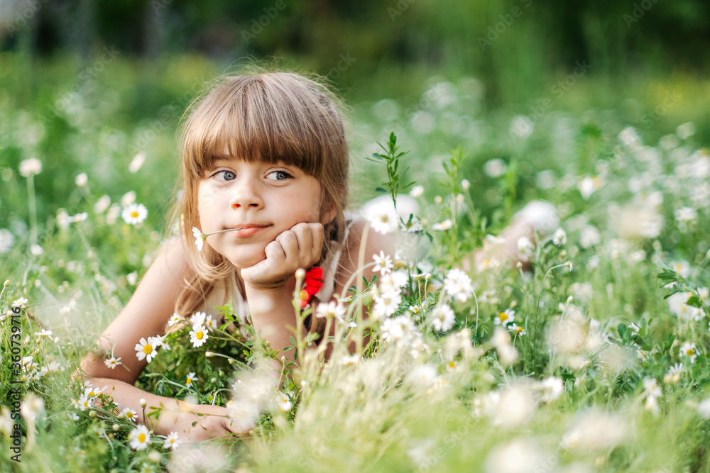 Pretty girl lying in daisy field and smiling to camera, unity with ...