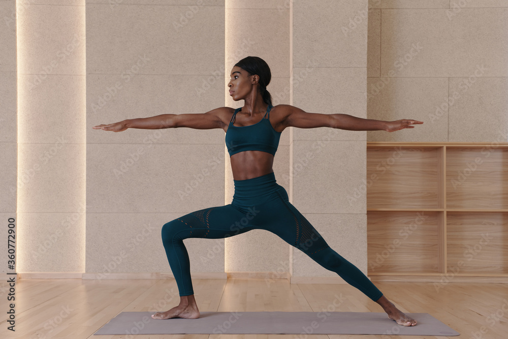Young black woman practicing yoga, doing Virabhadrasana 2 exercise ...