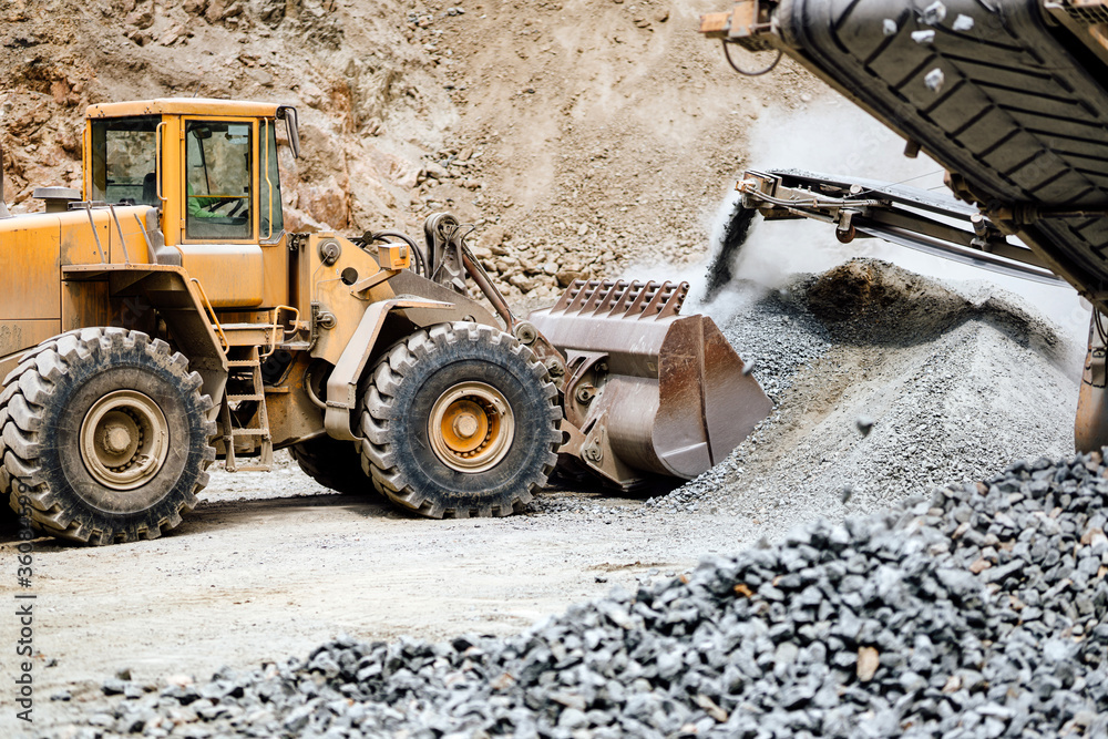 Heavy duty wheel loader machine loading rocks in the open mine, iron ...