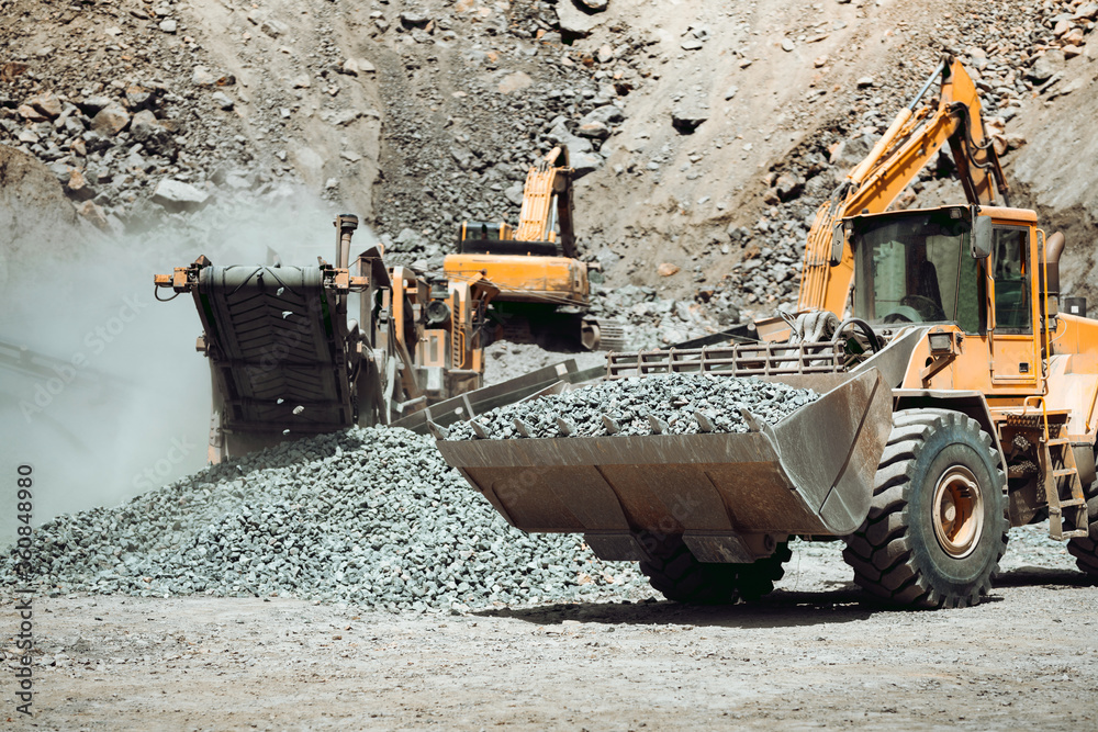 Large wheel loader on construction site transporting and loading gravel ...