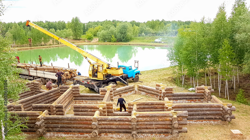 Building a house from a log. A group of men install a log house on a ...