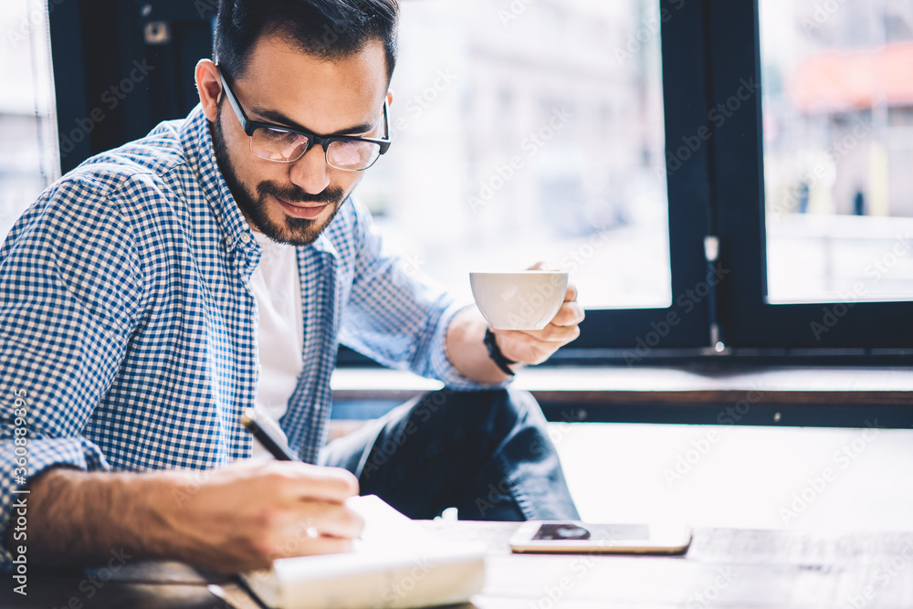 Clever male student concentrated on doing homework task writing in ...
