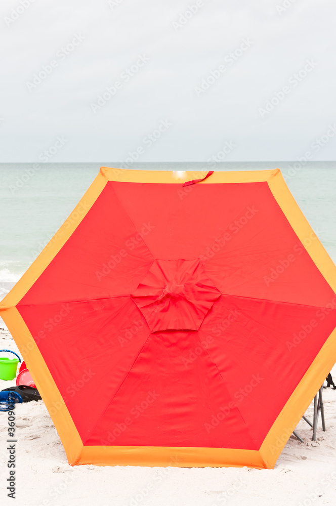 Back view of an orange beach umbrella with a yellow tri , on side being ...