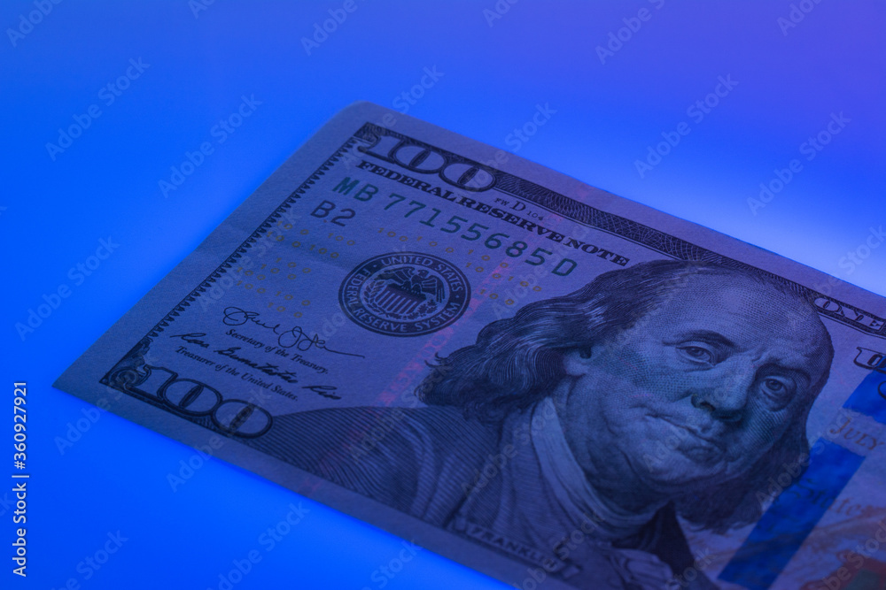 Checking 100 dollar banknote with ultraviolet lamp. Examining hundred ...