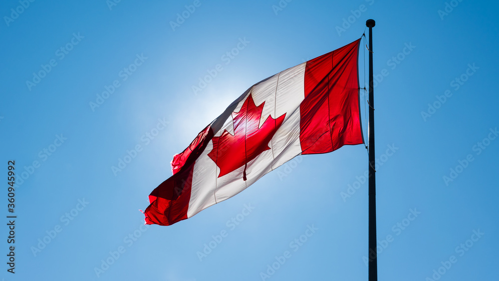 Bright red Canada Day flag pole waving and flapping in the wind ...