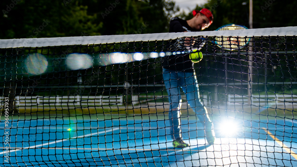 Close up of the silhouette of a man playing tennis and beating the ball ...
