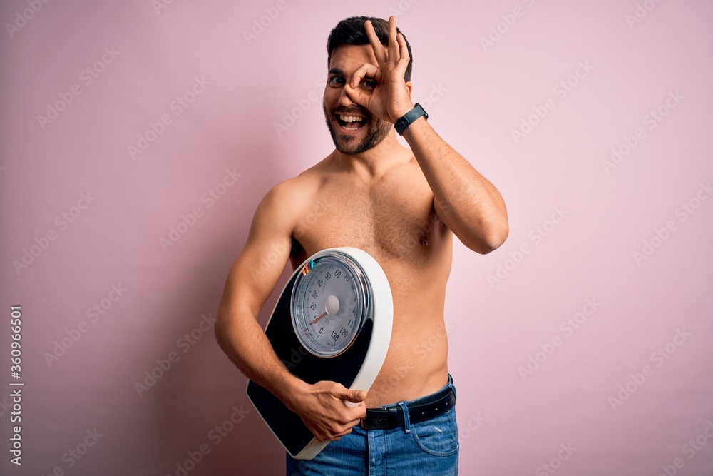 Young handsome slim man with beard shirtless holding weight machine ...