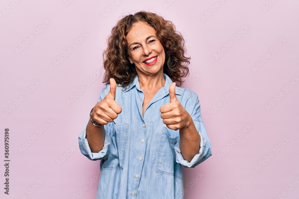 Middle age beautiful woman wearing casual denim shirt standing over ...