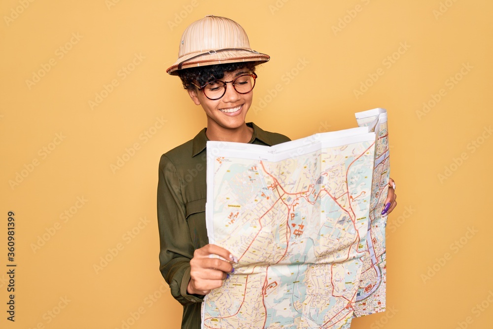 Beautiful african american explorer woman wearing hat holding city map ...