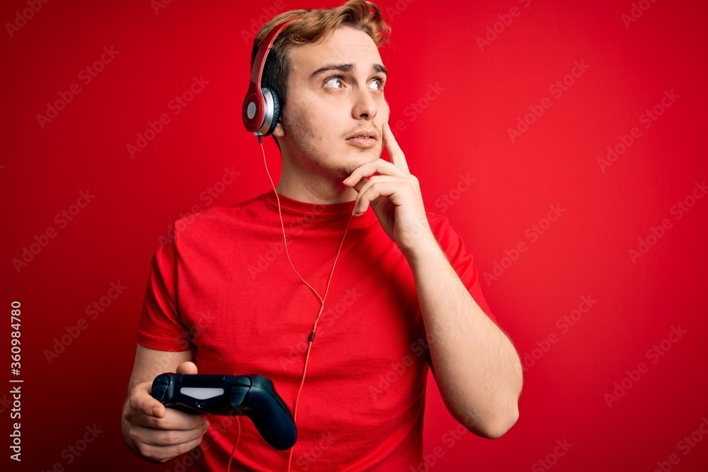 Young handsome redhead gamer man playing video game using headphones ...