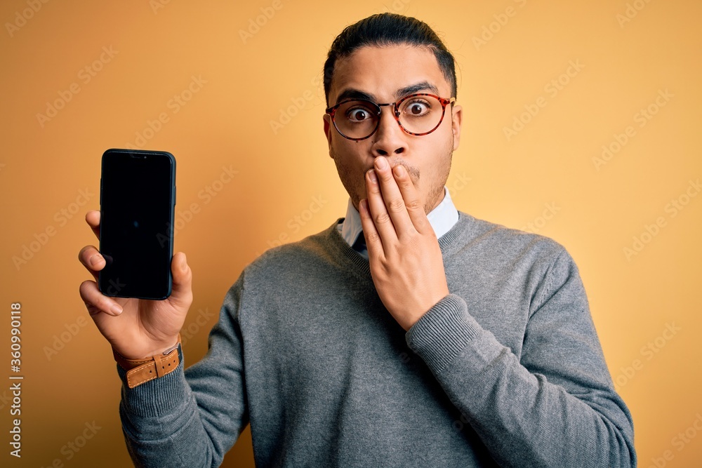 Young brazilian businessman wearing glasses holding smartphone showing ...