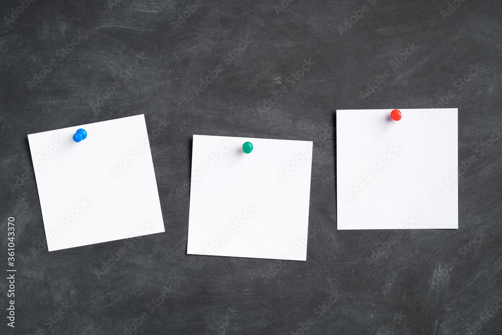 White paper sticky notes with pin clips on black board. Memo sticky ...