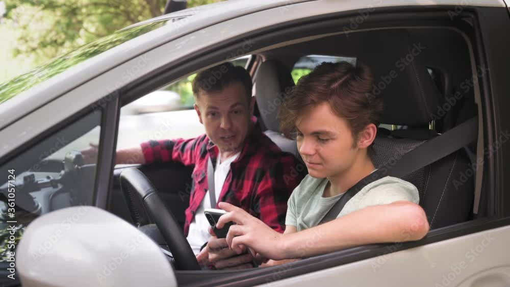 Teen boy in car using mobile phone. Nervous father shouting at child ...