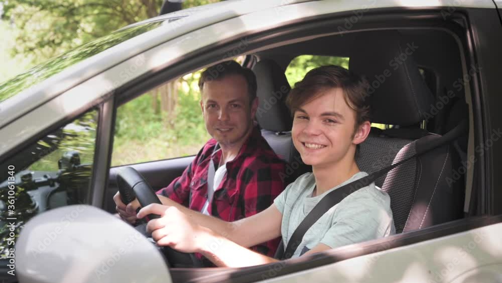 Teen boy trying to drive car. Young driver and his father smiling into ...