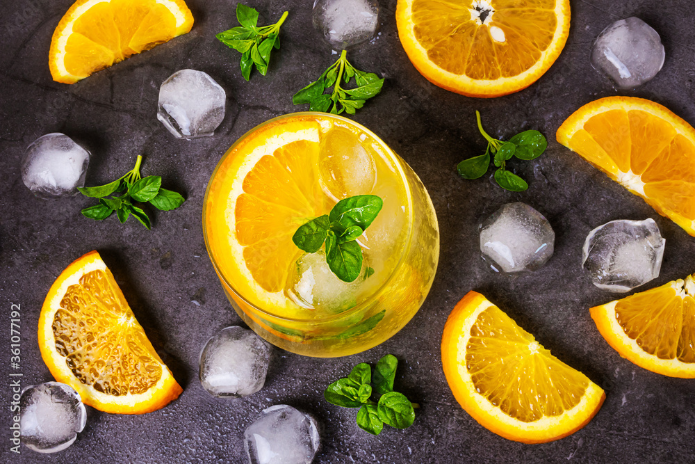Orange cold cocktail in transparent glass on dark background. Around ...