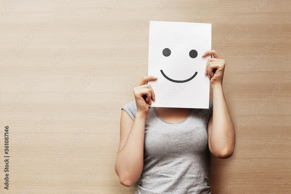 The person covers his face with an image of a painted smile. Hiding ...