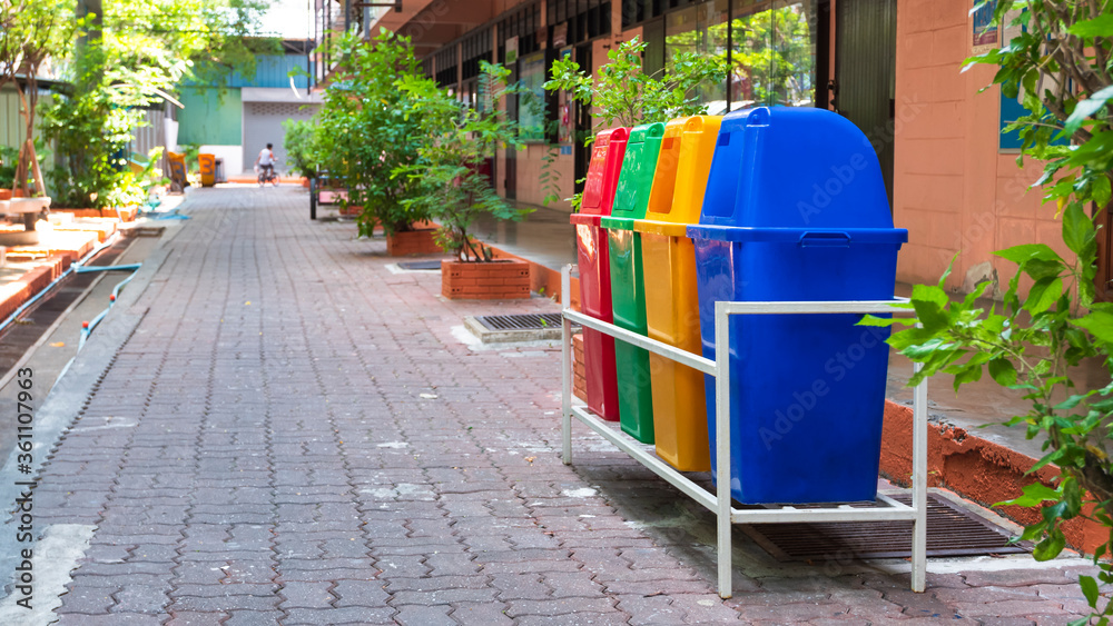 Perspective and side view of multicolored garbage bins on brick ...