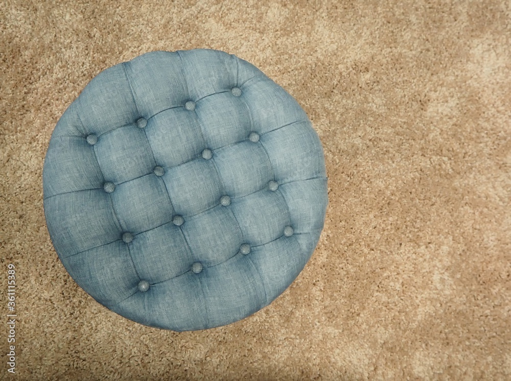 Top view of round fabric blue pouf with buttons and squares. Brown ...