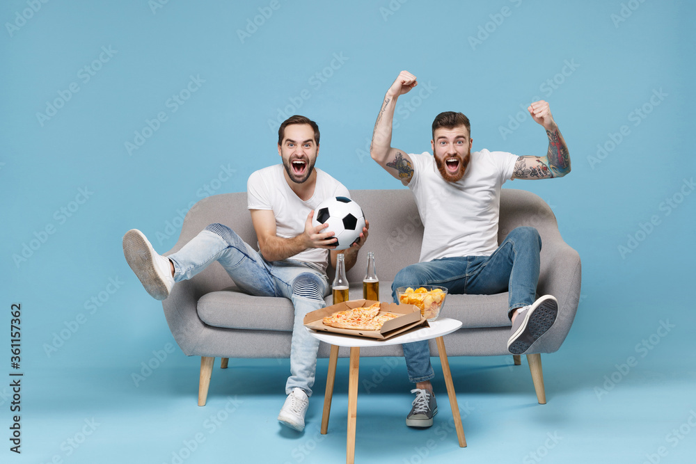 Foto Stock Excited men guys friends in white t-shirt sit on couch ...