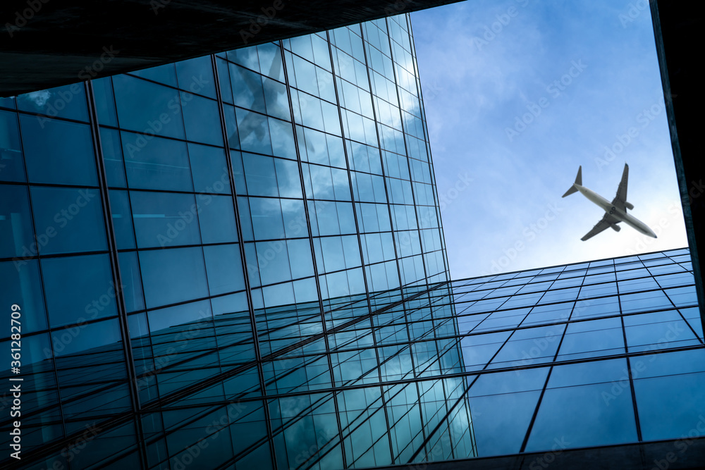 Airplane flying above modern glass office building. Perspective view of ...