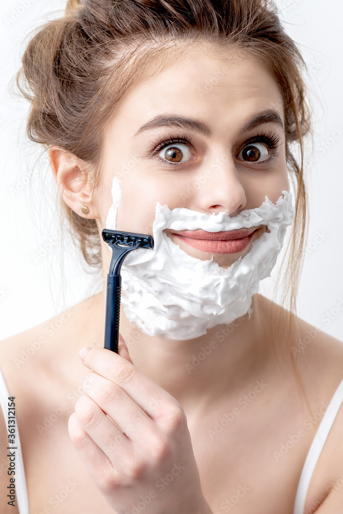 Beautiful young caucasian woman shaving her face by razor on white ...
