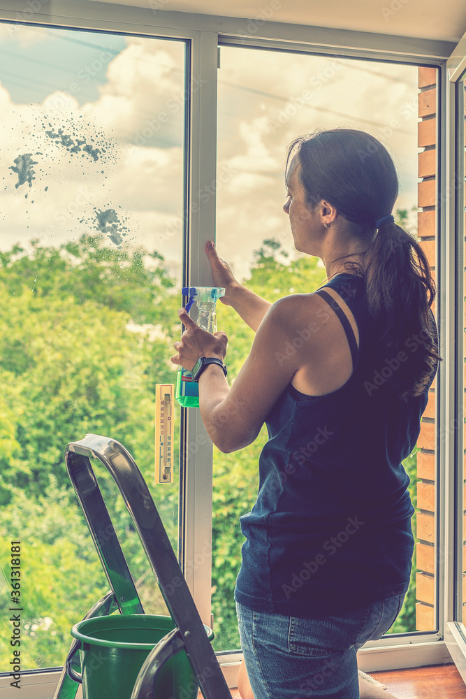 Back view of the young woman who washing the window with rag and window ...
