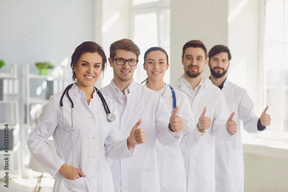Young smiling doctors team portrait with thumbs up gesture in modern ...