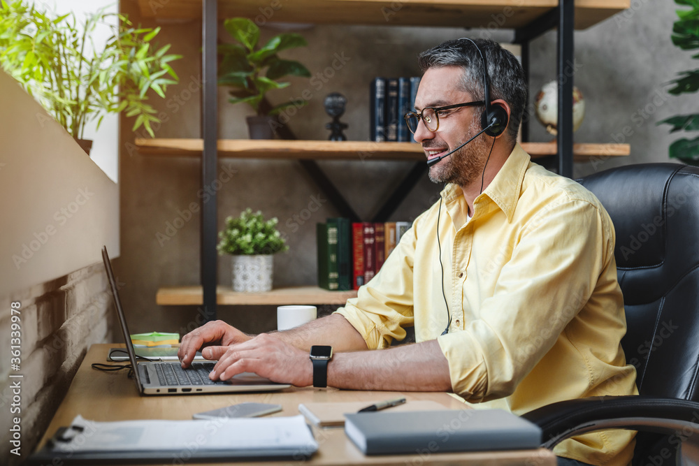 Man in front of desk with laptop computer and headset working Stock ...