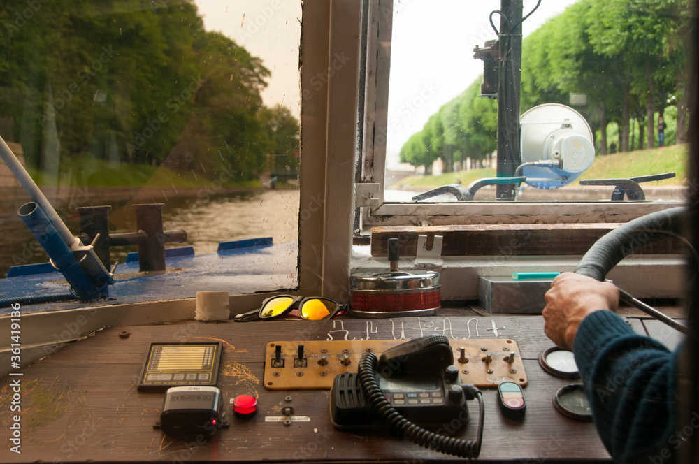 Deckhouse of the ship. Helmsman‘s hand on a steering wheel. Looking ...
