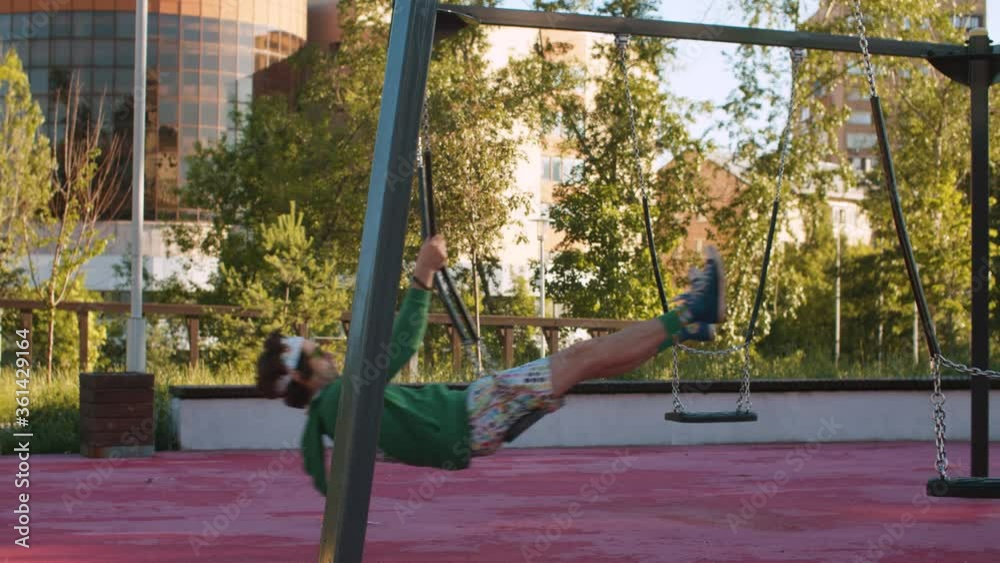 Funny freak man swinging on a swing on kids playground in the park ...