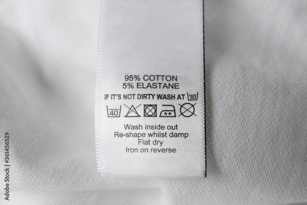 Clothing label with care symbols and material content on white shirt ...