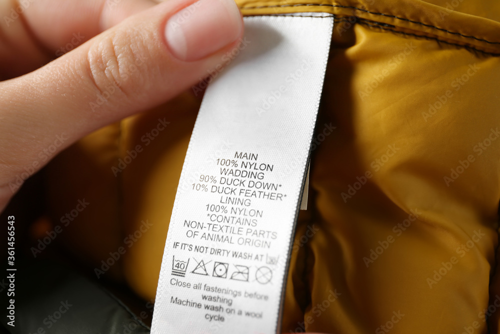 Woman reading clothing label with care symbols and material content on ...