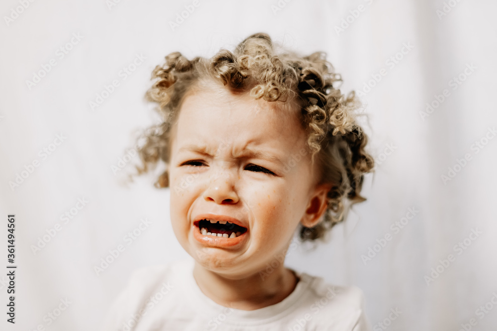 Little curly girl is crying very emotionally, face with tears and ...