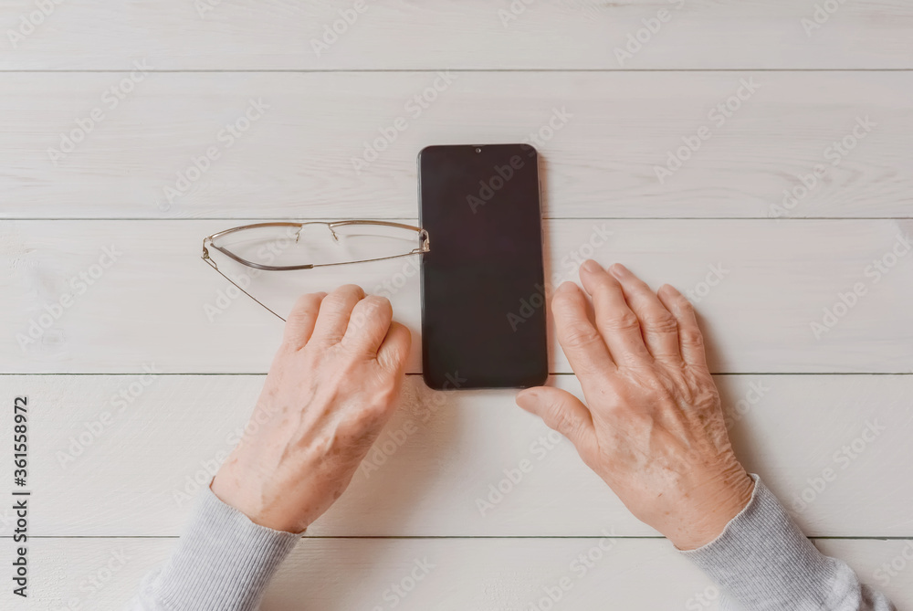 Old wrinkled hands holding mobile smart phone. Elderly woman using ...