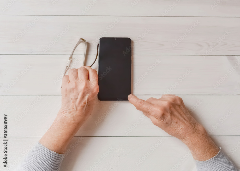 Old wrinkled hands holding mobile smart phone. Elderly woman using ...