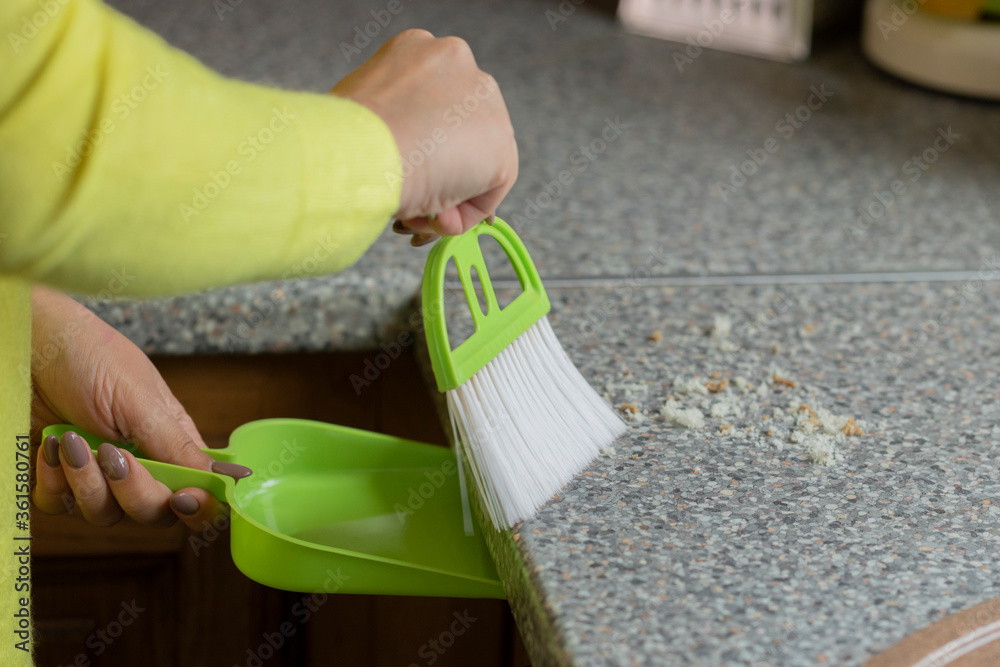Girls' hands sweeping garbage bread crumbs off gray kitchen table close ...
