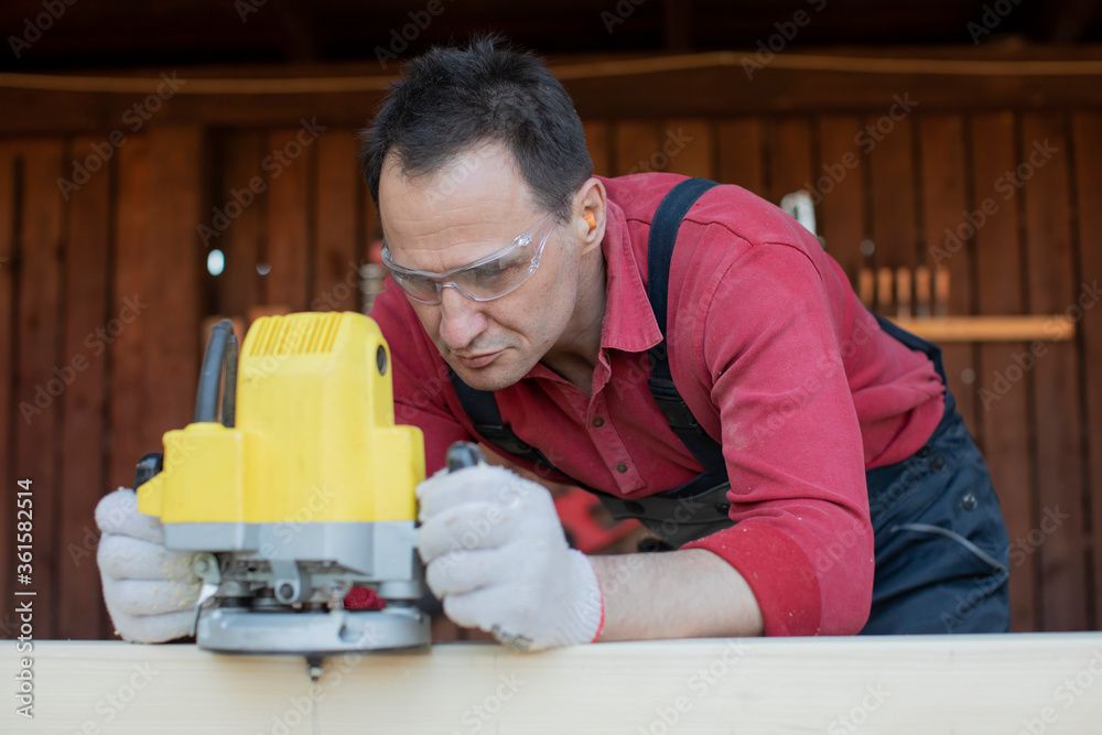 Craftsman carpenter works on wooden workpiece with milling tool close ...