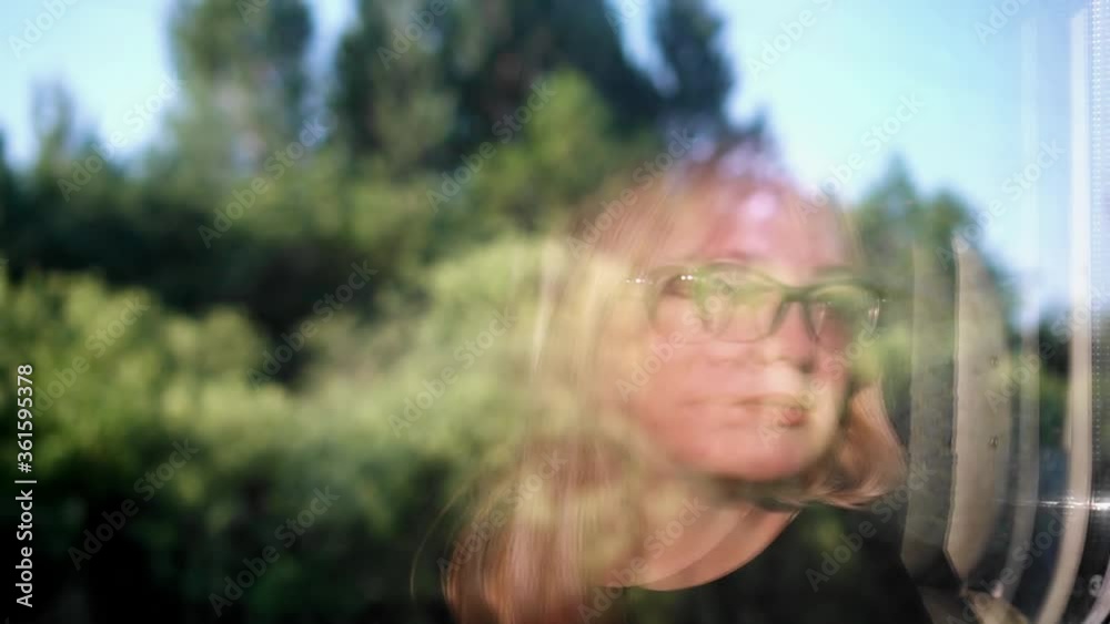 Reflection of a woman's face in the glass of a train window while ...