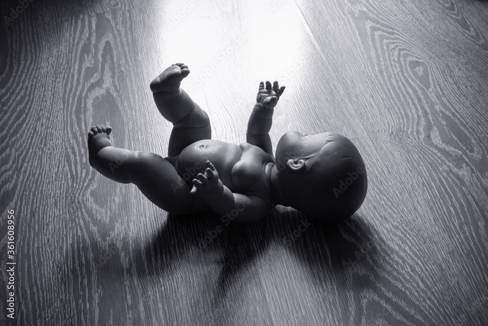 Baby doll on a wooden floor, symbol of abortion, dead child ...