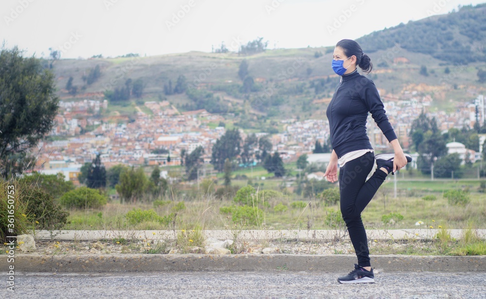 Mujer con máscara estirando sus músculos para correr y ejercitarse ...