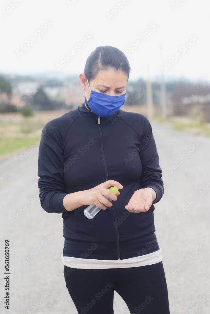 Mujer atlética aplicando desinfectante en sus manos mientras sale a la ...