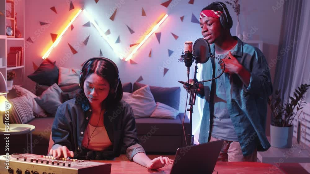 Vidéo Stock Multiethnic music duo recording hip-hop at home studio ...